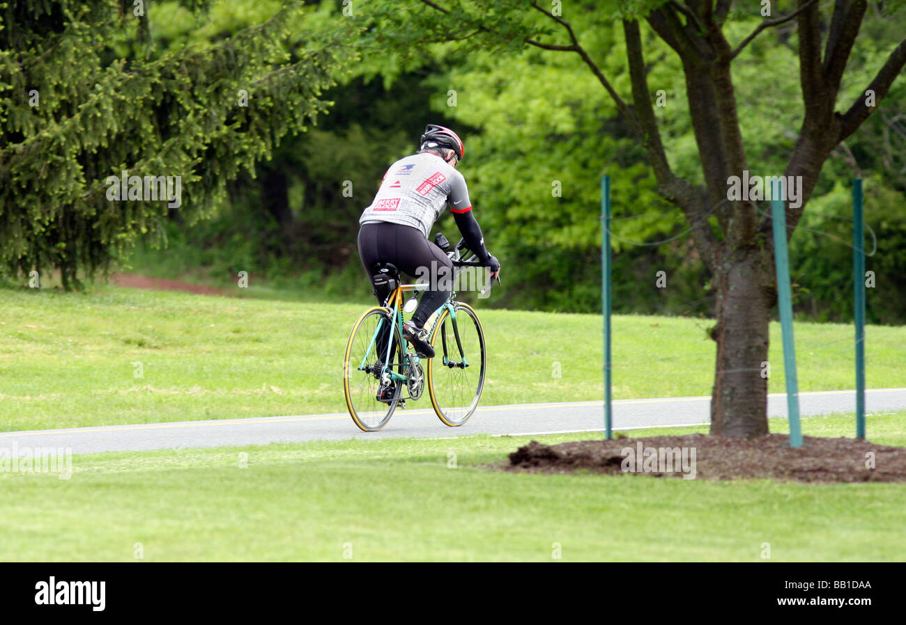 A bicycle rider in full gear leaving a parking lot Stock Photo - Alamy