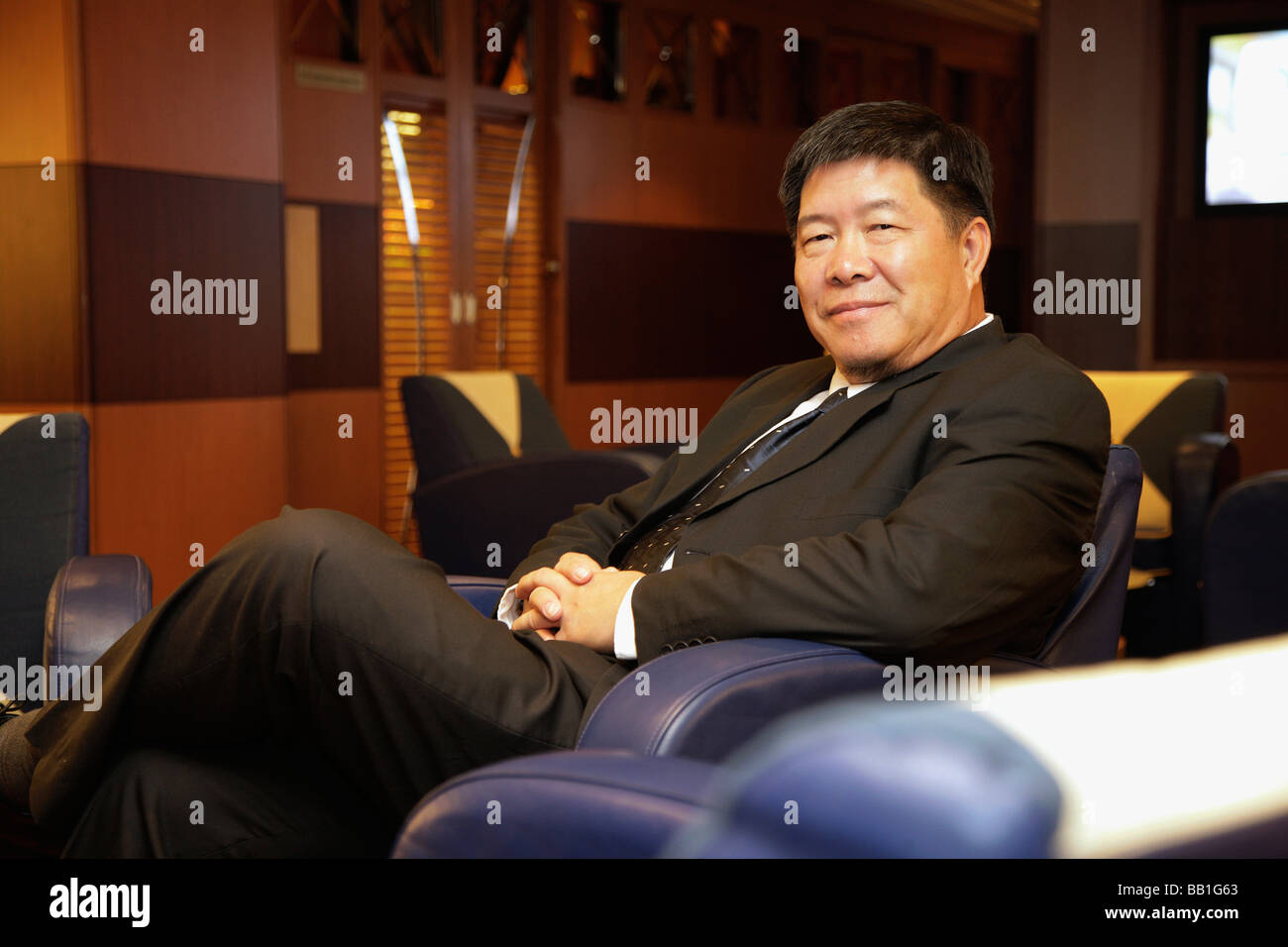 Chinese man in suit sitting on sofa Stock Photo - Alamy