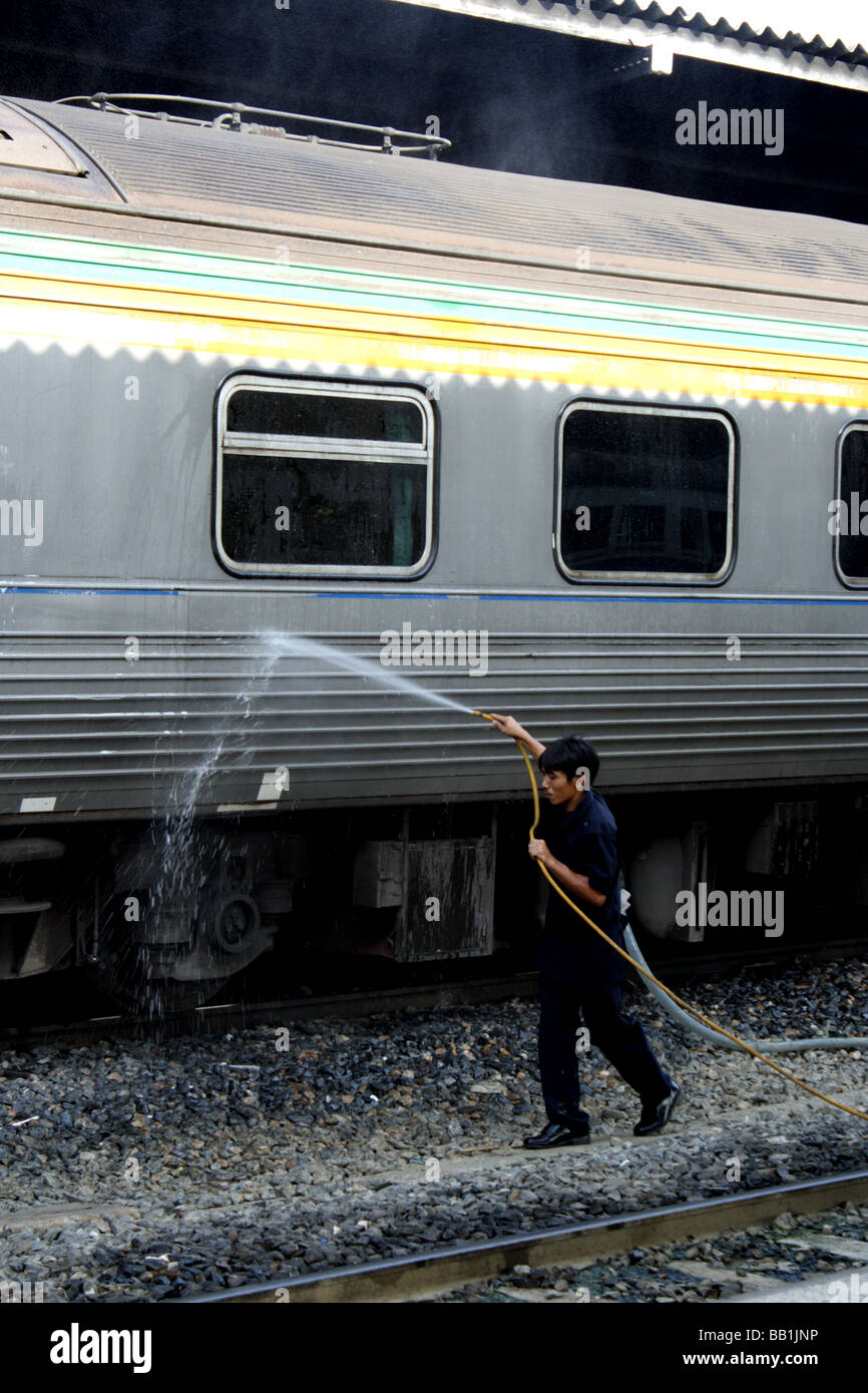 A man washing a train at Hualumphong Train Station , Bangkok , Thailand ...