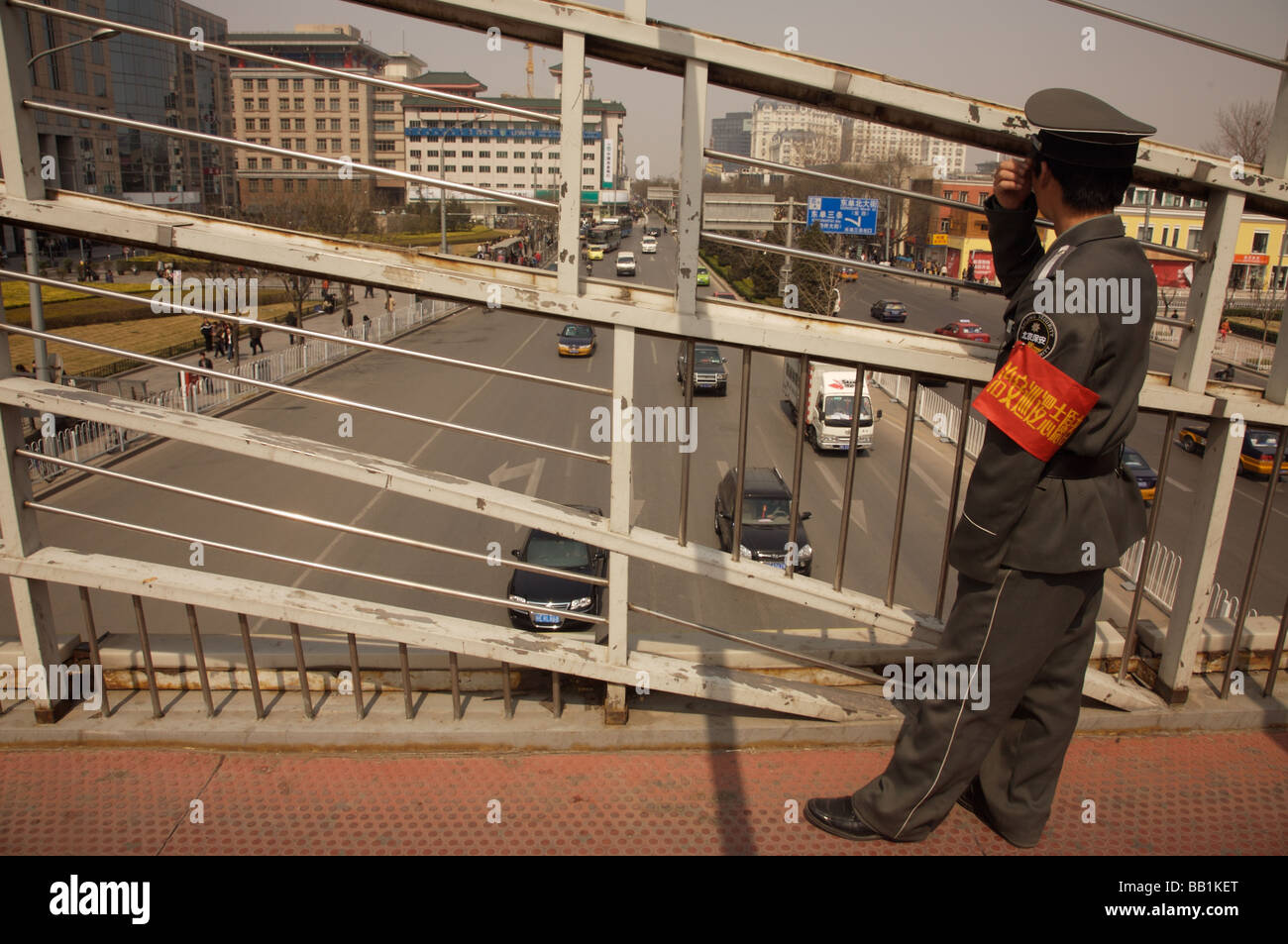 A young guard on a bridge in Beijing watching the traffic on the road ...