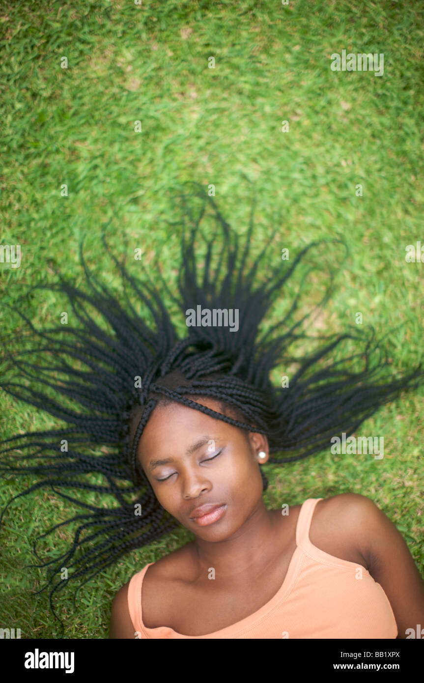 Woman with dreadlocks laying on grass in garden, Pietermaritzburg ...