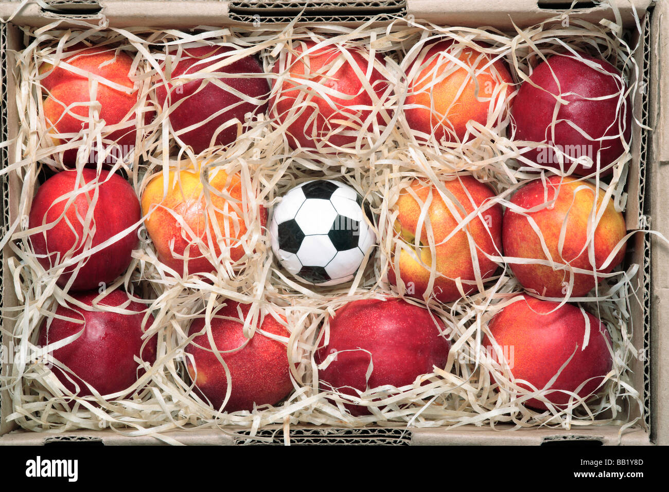 Studio shot of small football among nectarine fruits in fruit box ...