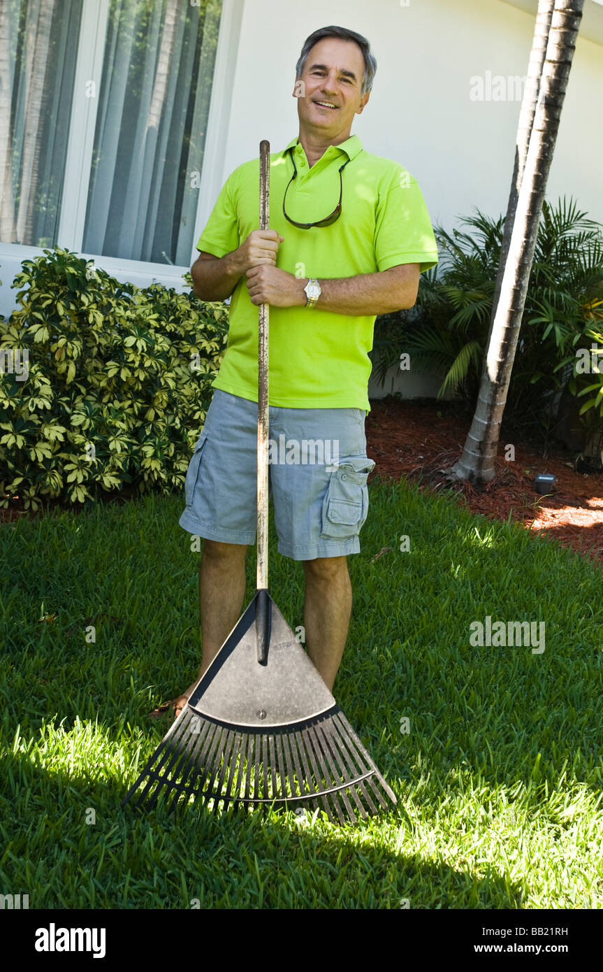Man holding a rake in the lawn Stock Photo - Alamy