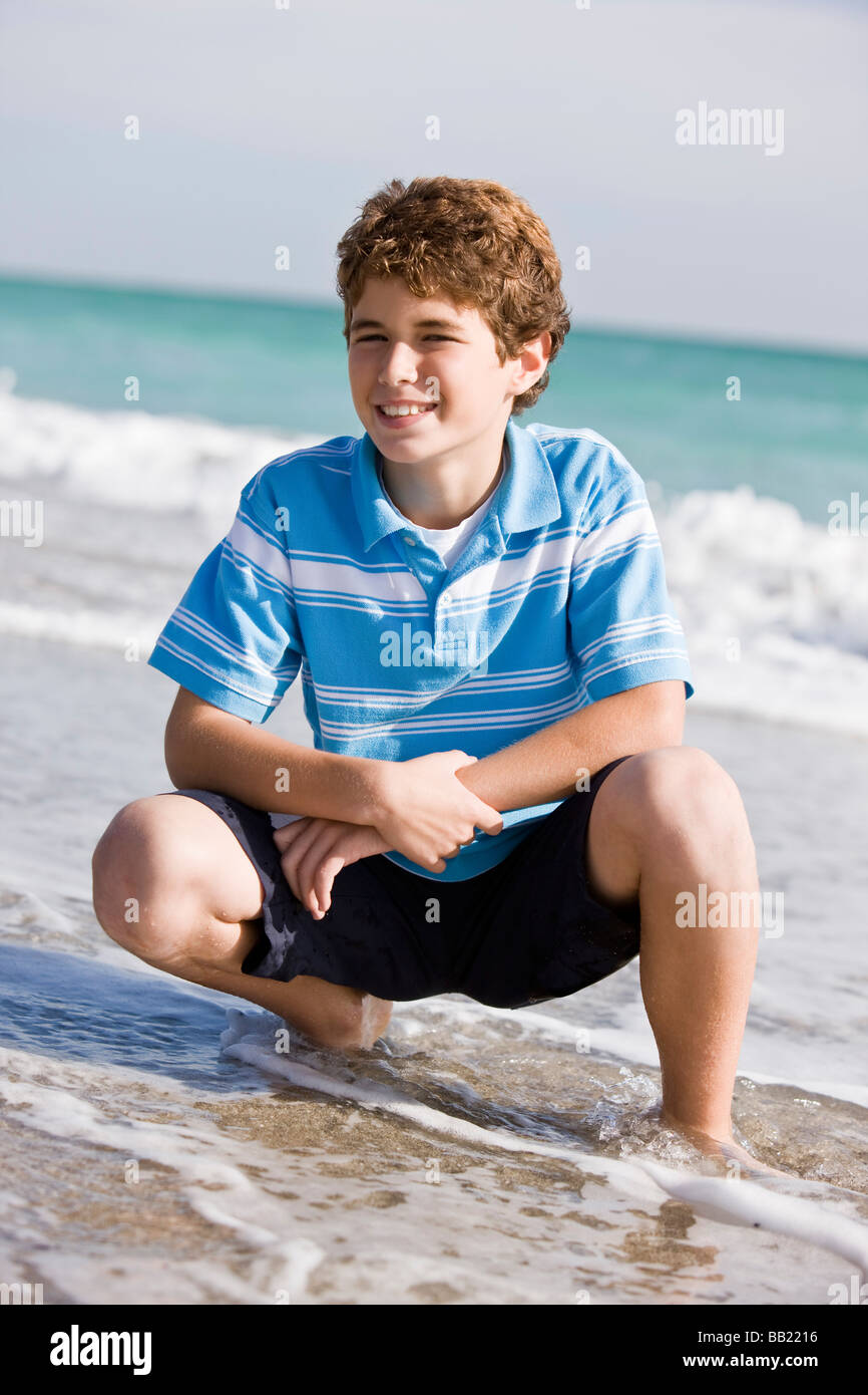 Boy crouching on the beach Stock Photo - Alamy