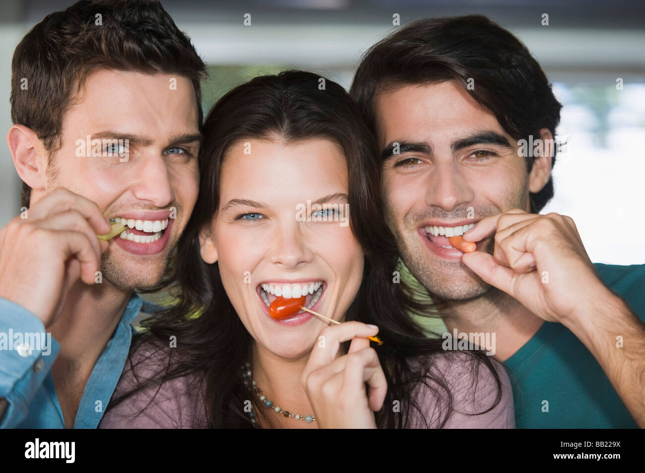 Portrait of three friends eating fruits Stock Photo - Alamy