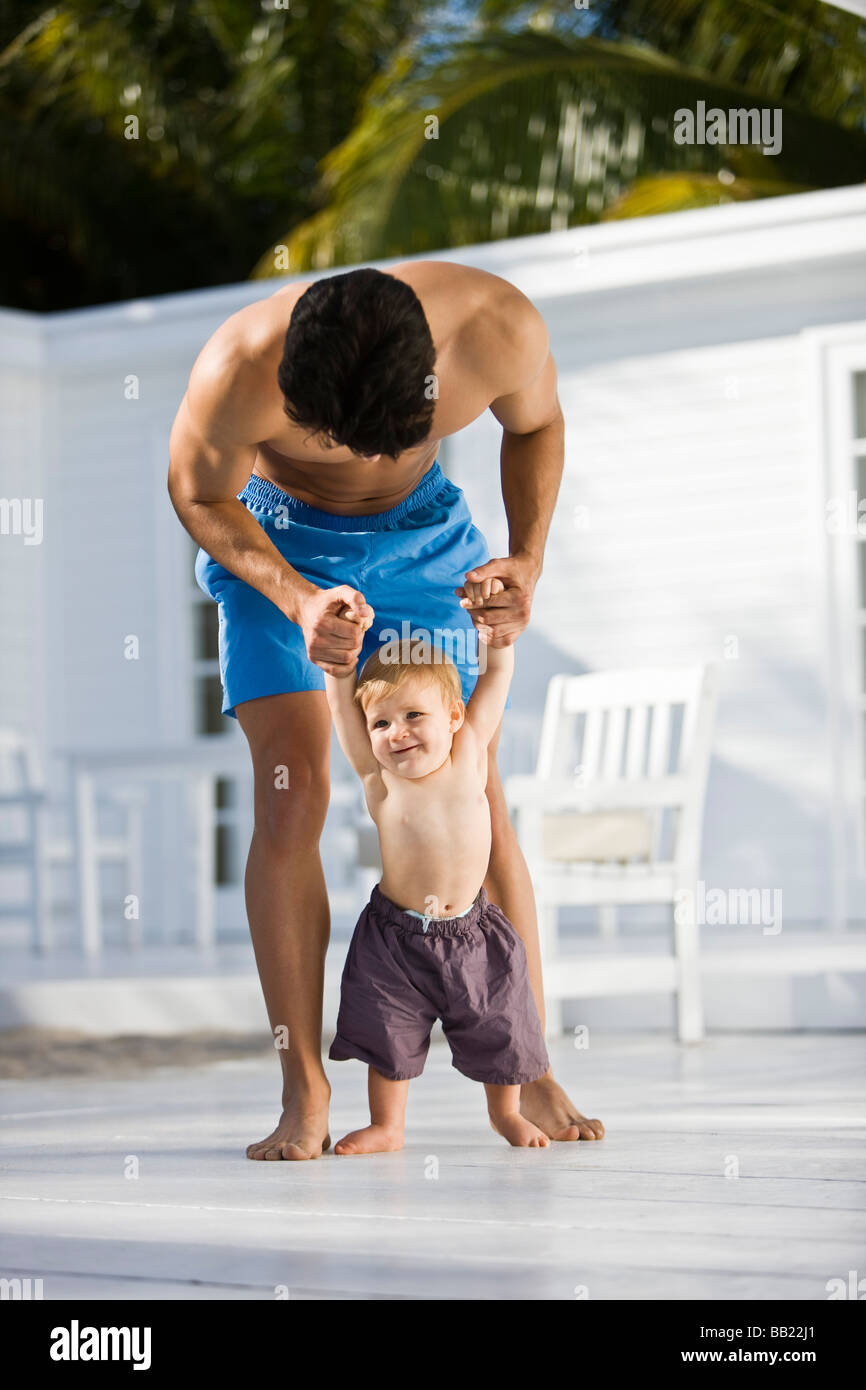 Man helping his son to walk Stock Photo - Alamy