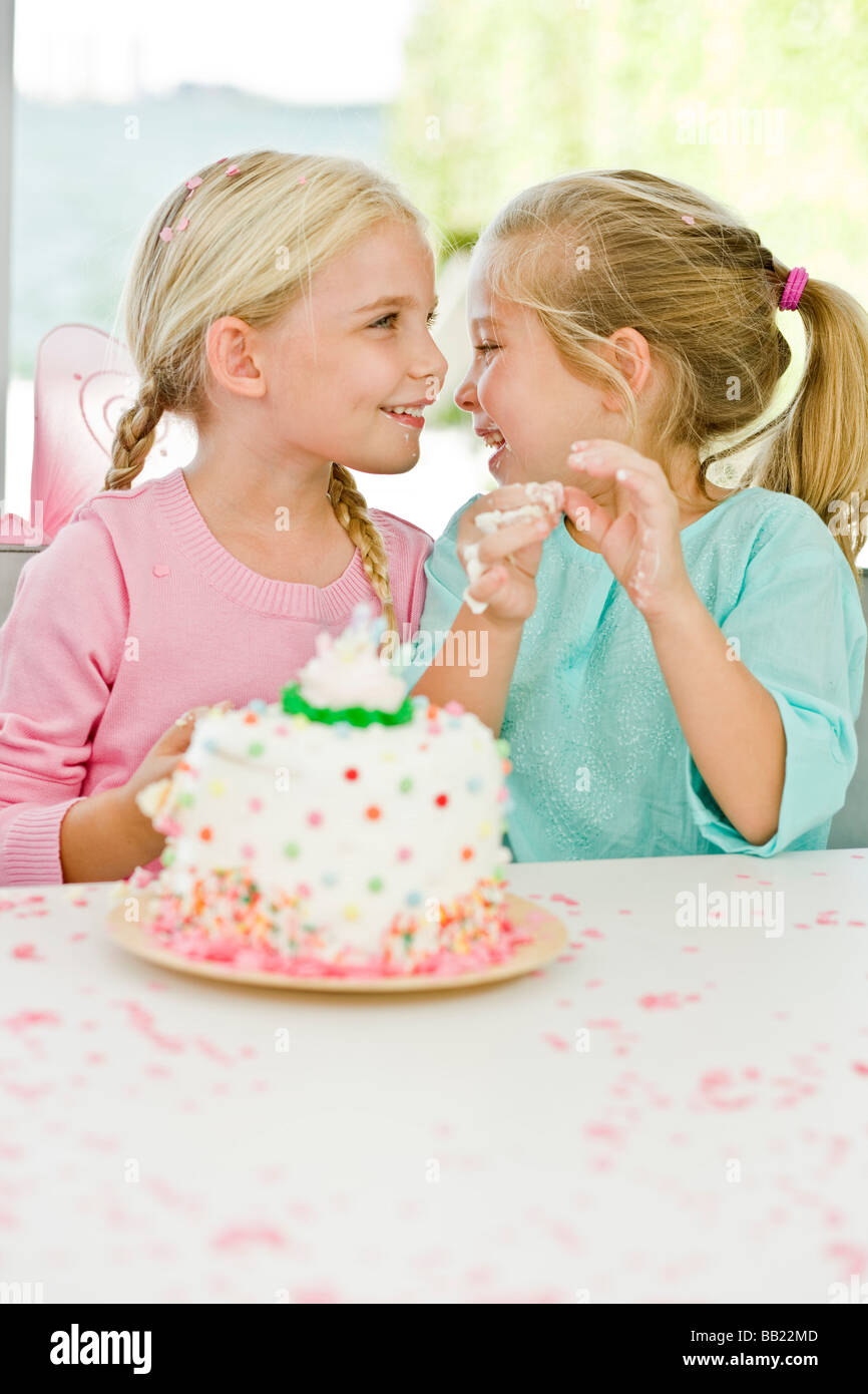 Two girls smiling in front of a birthday cake Stock Photo - Alamy
