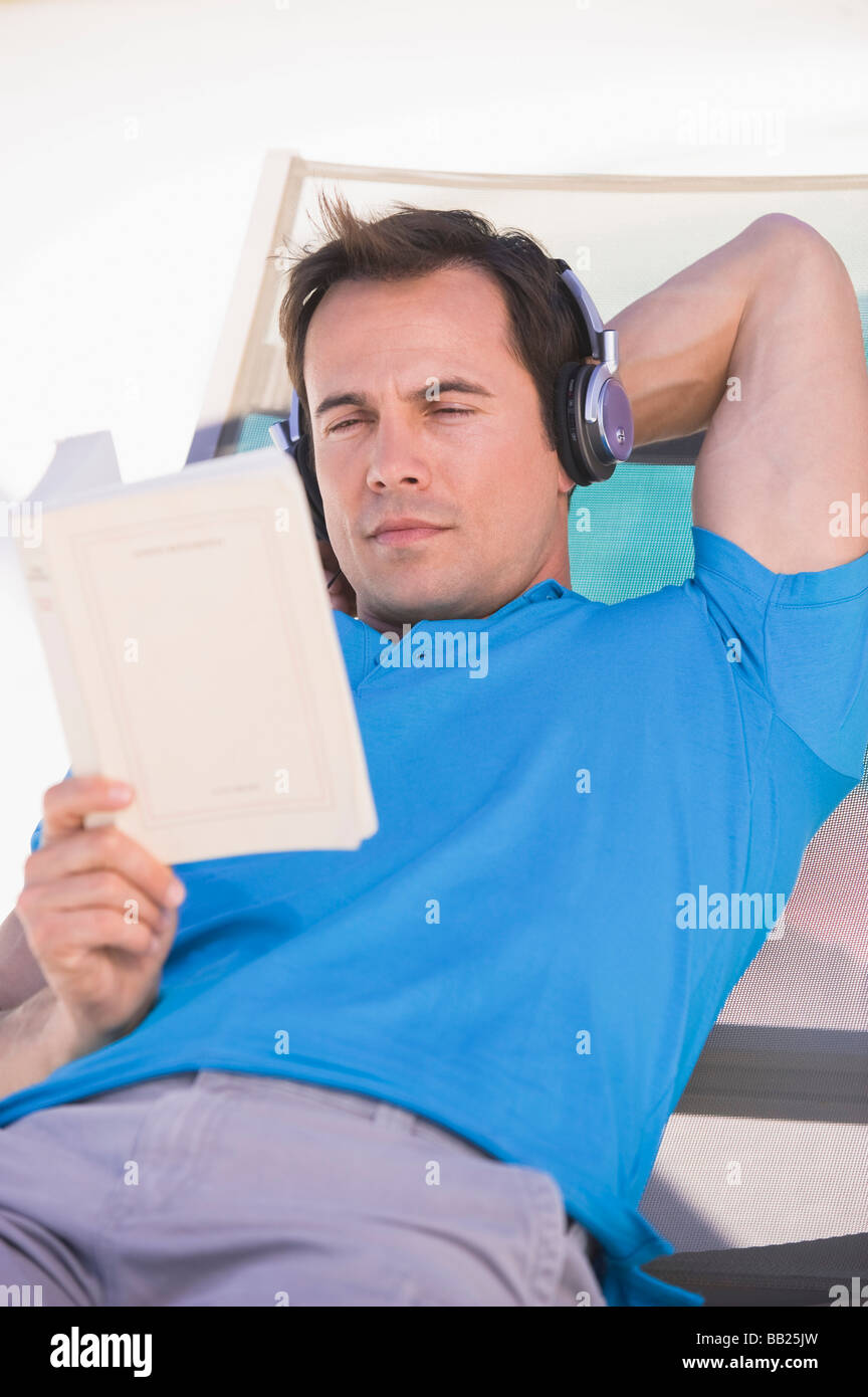 Man reading a book on a lounge chair Stock Photo - Alamy