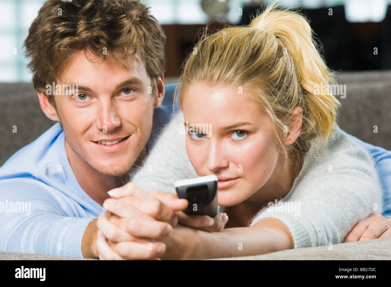 Portrait of a couple holding a remote control and smiling Stock Photo ...