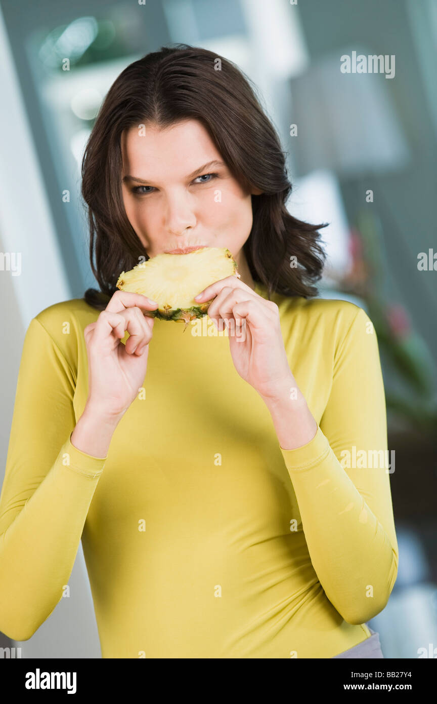 Portrait of a woman sucking a slice of pineapple Stock Photo - Alamy