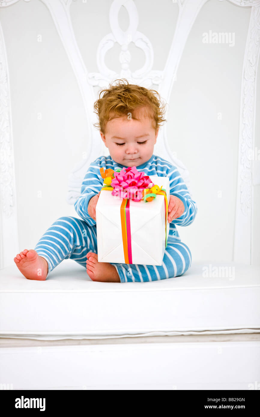 Baby boy holding a present in an armchair Stock Photo - Alamy
