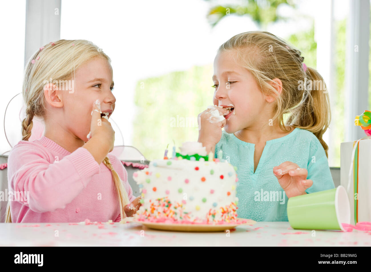 Two girls eating birthday cake Stock Photo - Alamy