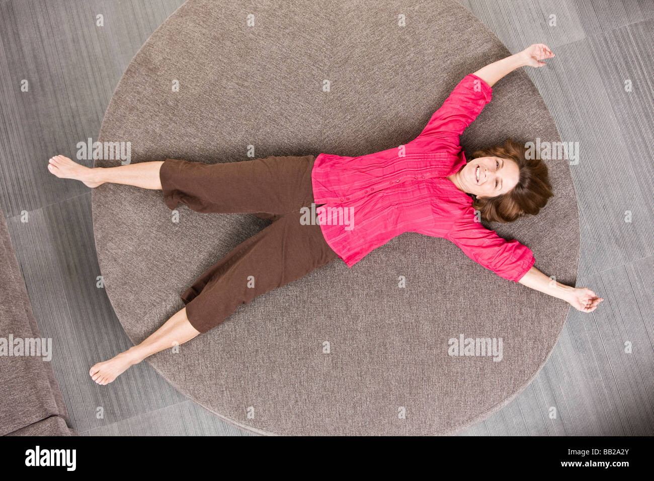 Woman lying on a round sofa Stock Photo - Alamy