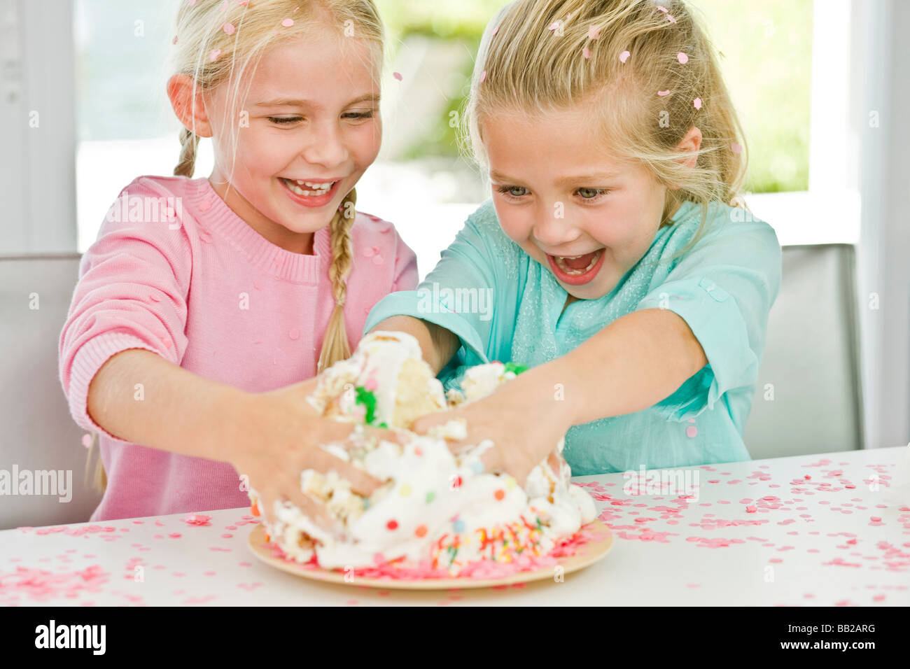 Two girls playfully inserting their hands in a birthday cake Stock ...