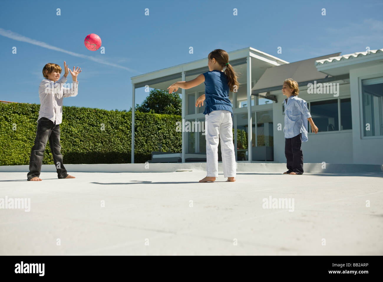 Three children playing with a ball Stock Photo - Alamy