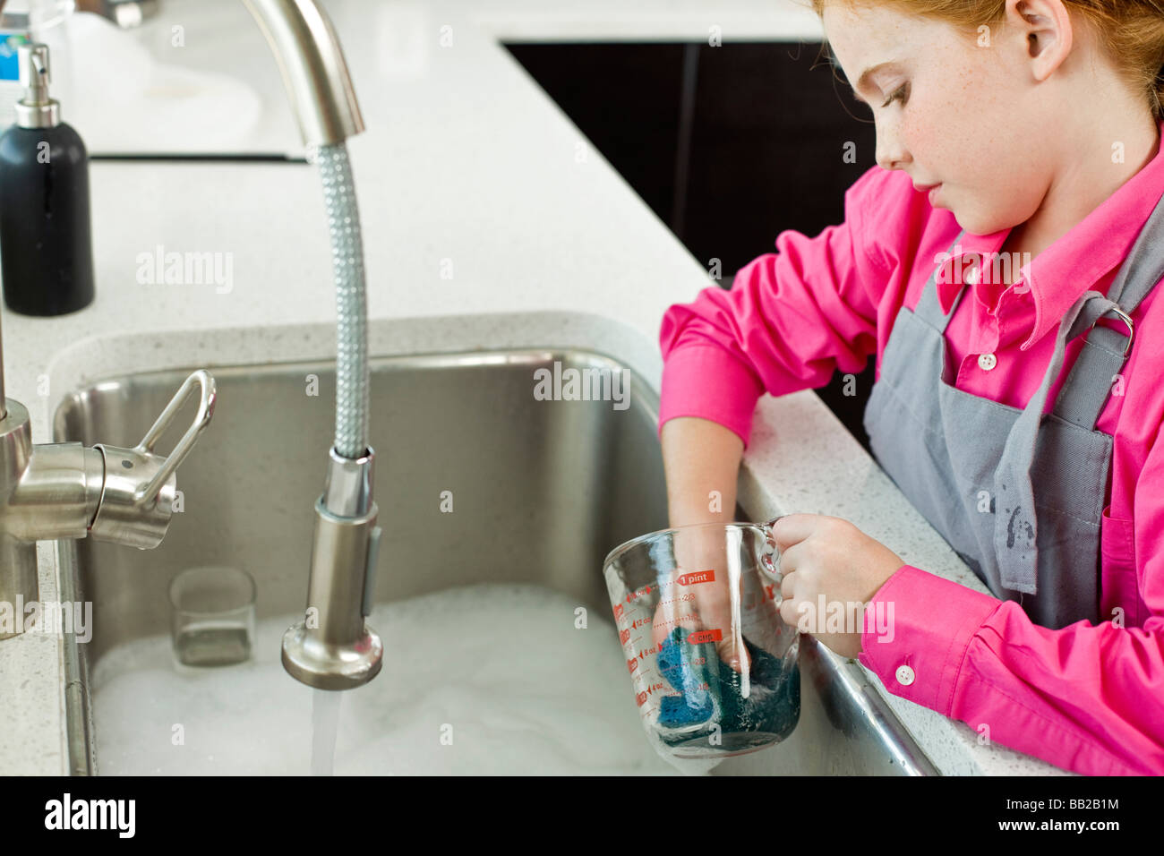 Girl washing a measuring jug at a sink Stock Photo - Alamy