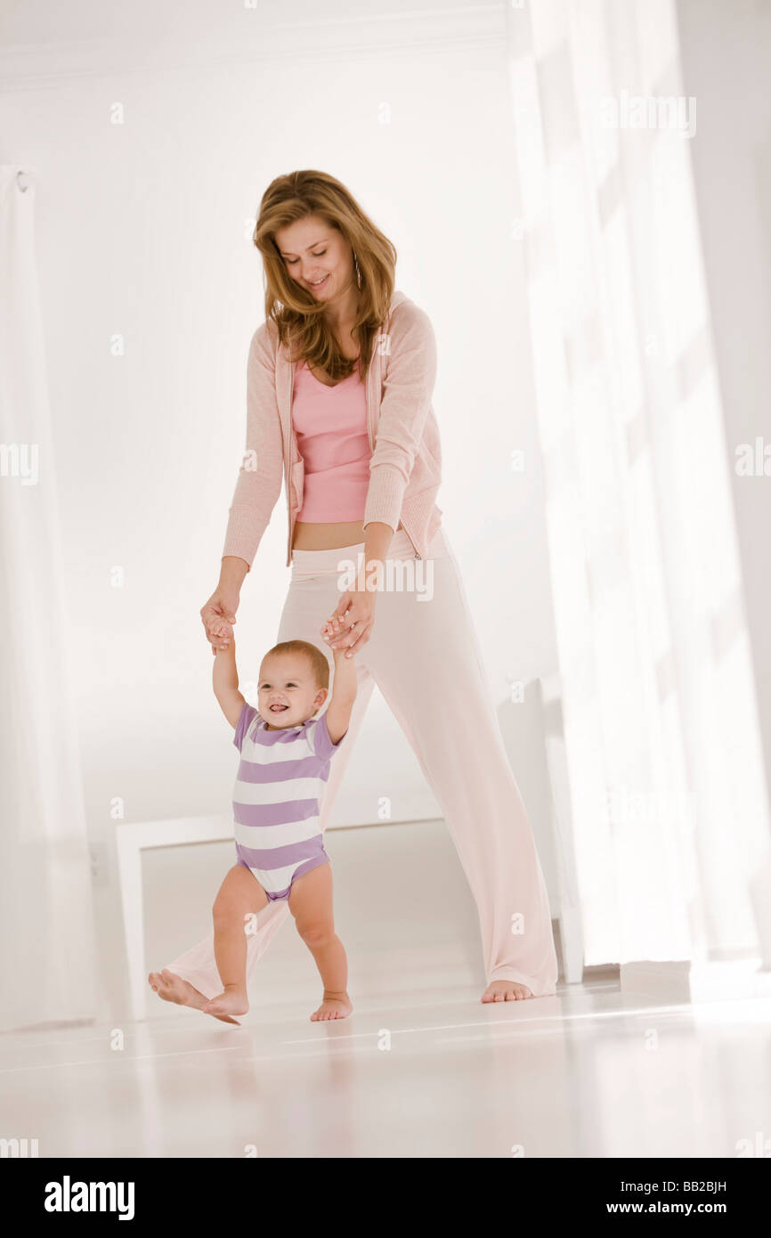 Woman helping her daughter to walk Stock Photo - Alamy