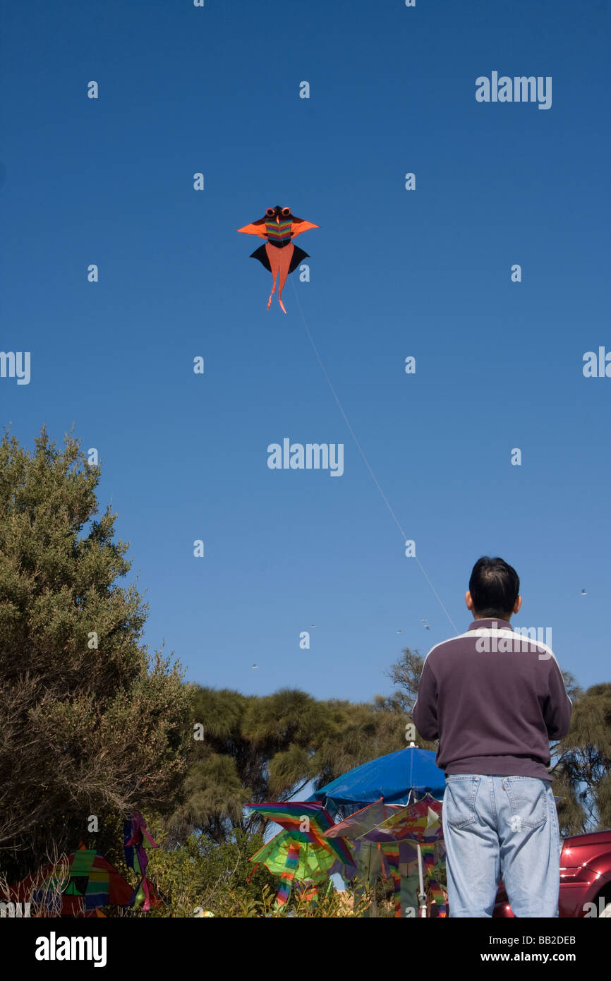 Flying an orange kite against an azure blue sky Stock Photo - Alamy
