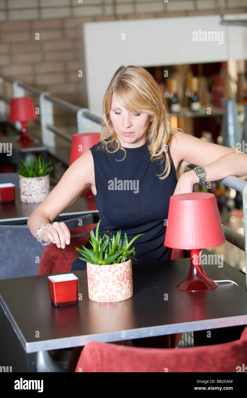 Pretty blond woman sitting in a restaurant waiting with a drink Stock ...