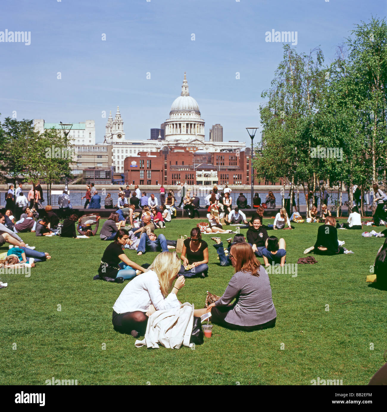 People relaxing in sunshine on the lawn outside the Tate Modern Art ...
