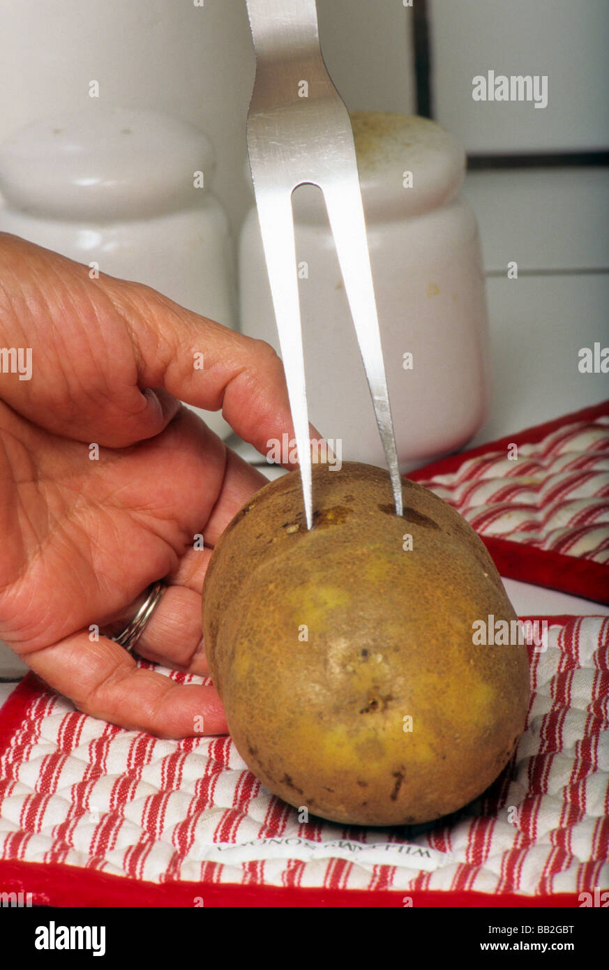 Woman cook bake potato oven hot insert prepare food poke fork Stock ...