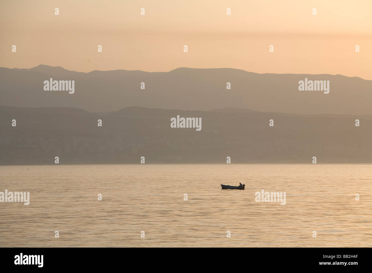 Traveling Croatia; The silhouette of a little boat is dwarfed by ...