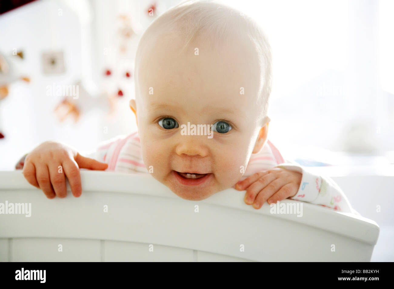 Cute baby looking over the top of her cot hi-res stock photography and ...
