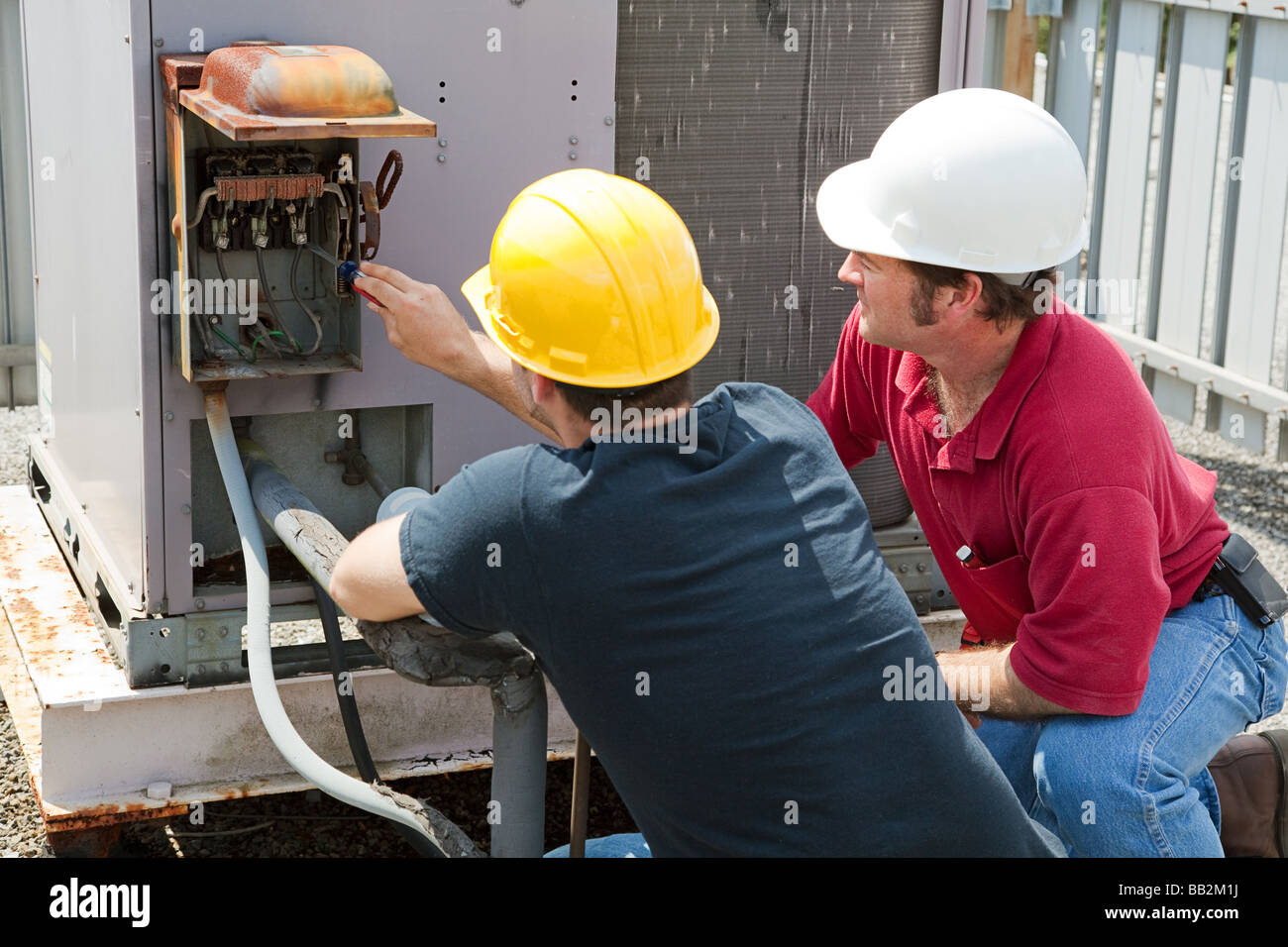 Two AC technicians repairing an industrial air conditioning compressor ...