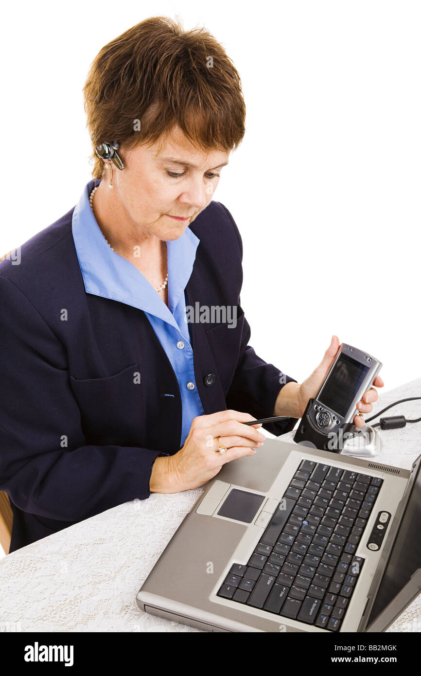 Businesswoman transferring data from her PDA to her laptop while ...