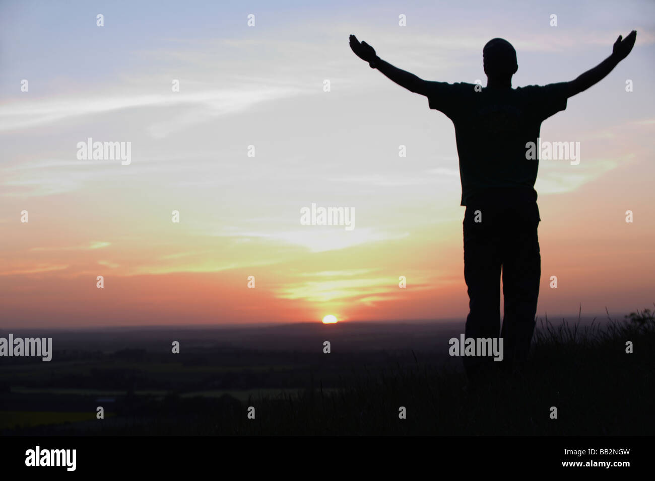man with arms outstretched in front of sunset Stock Photo - Alamy
