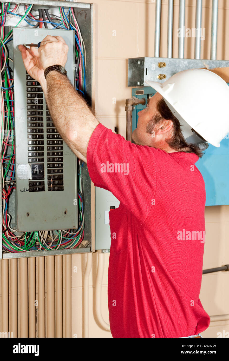 Licensed master electrician working on an industrial breaker panel ...
