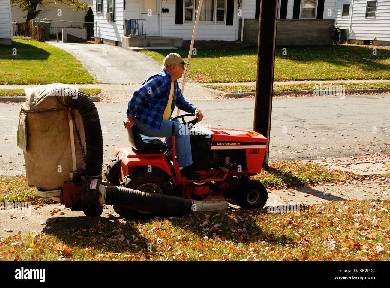 Man on tractor cleaning up leaves with a vacum bagger on back Stock ...