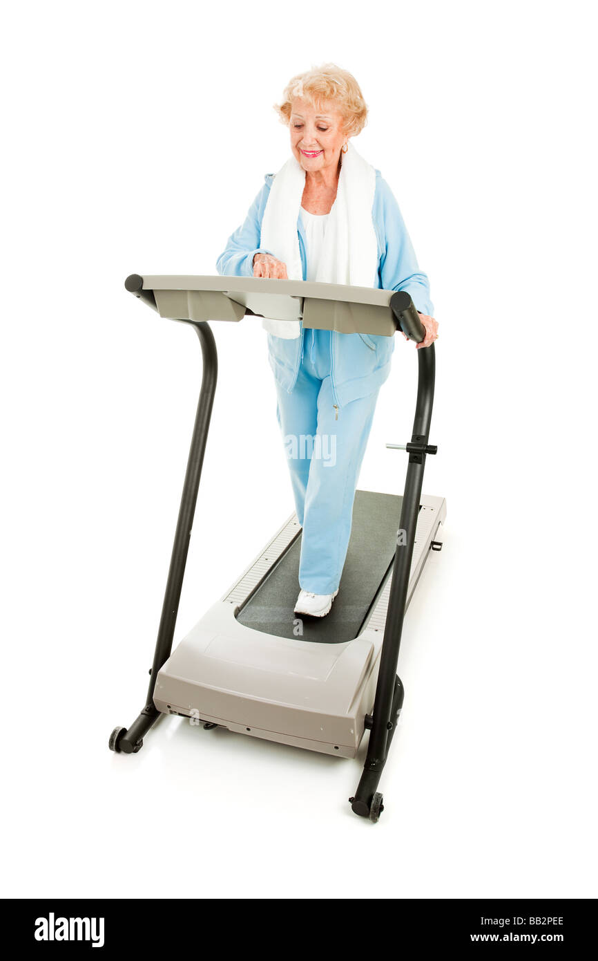 Healthy senior woman walking on a treadmill Full body isolated on white ...