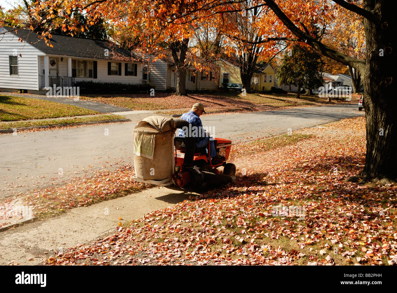 Man on tractor cleaning up leaves with a vacum bagger on back Stock ...