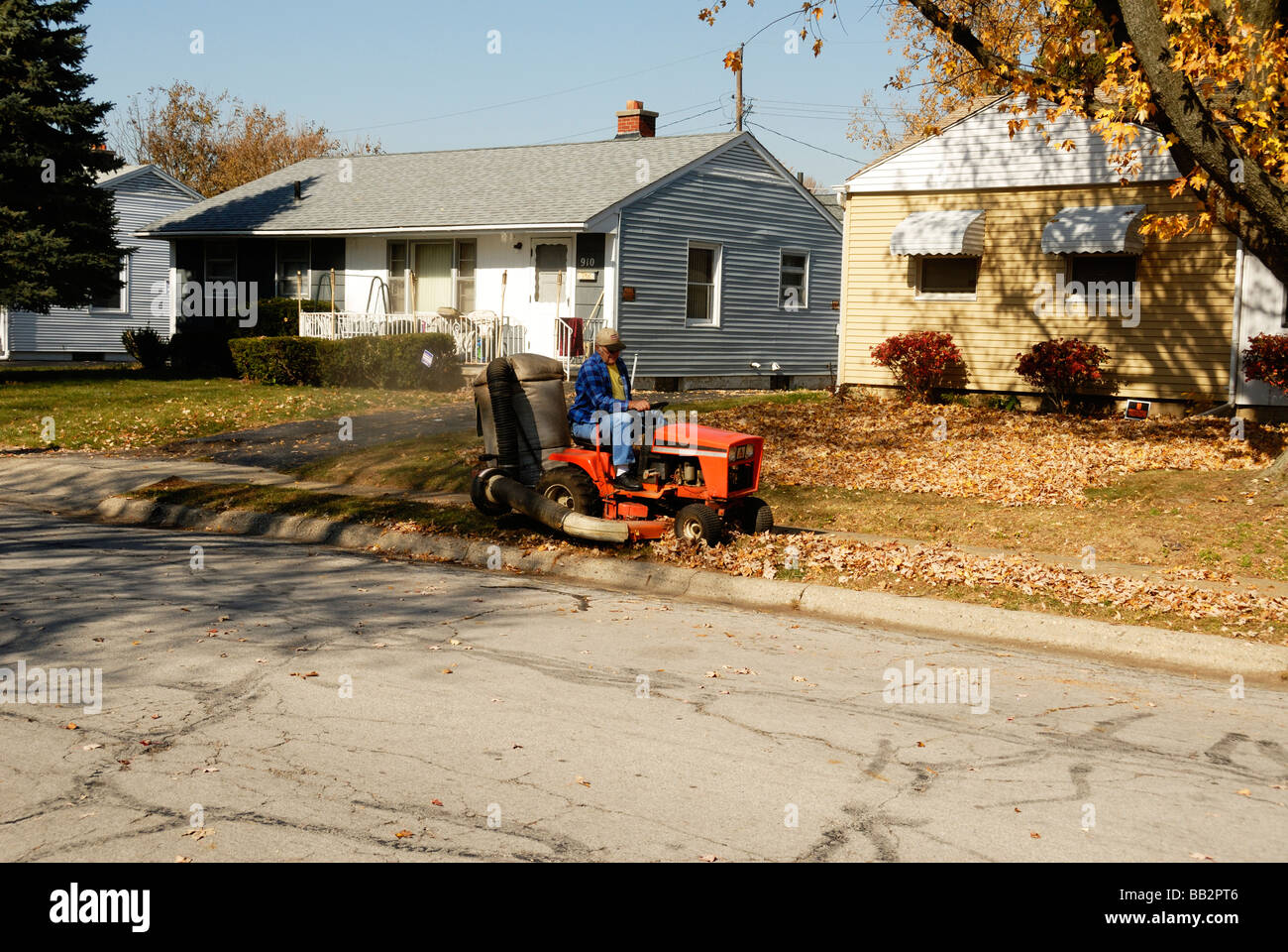 Man on tractor cleaning up leaves with a vacum bagger on back Stock ...