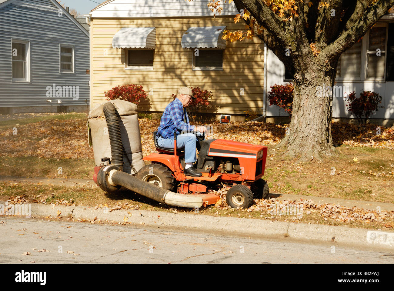 Man on tractor cleaning up leaves with a vacum bagger on back Stock ...