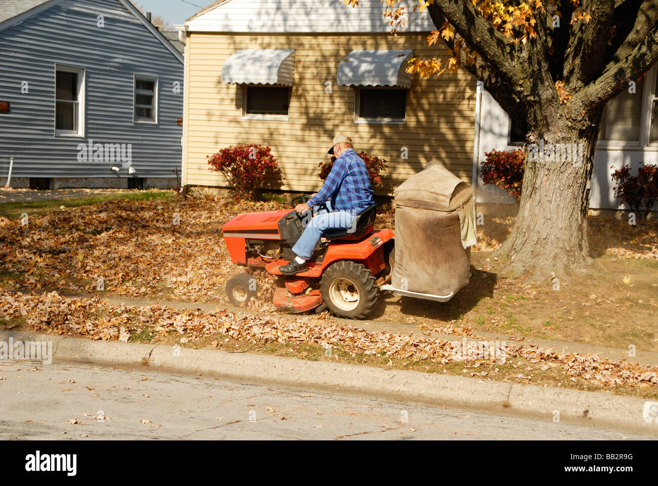 Man on tractor cleaning up leaves with a vacum bagger on back Stock ...