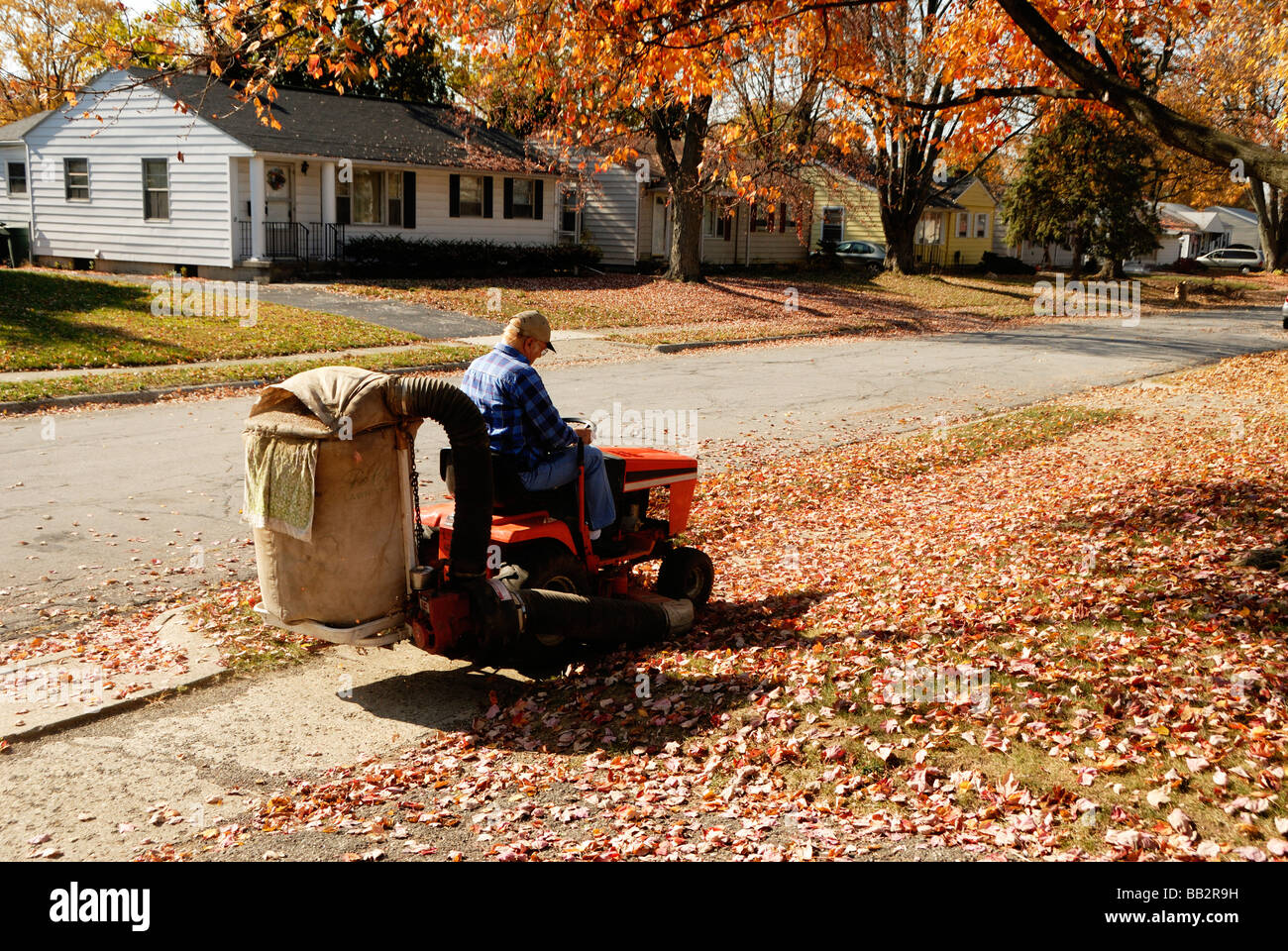 Man on tractor cleaning up leaves with a vacum bagger on back Stock ...
