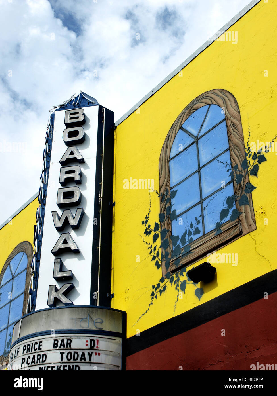 yellow commercial building with cloudy sky and large vertical sign with ...