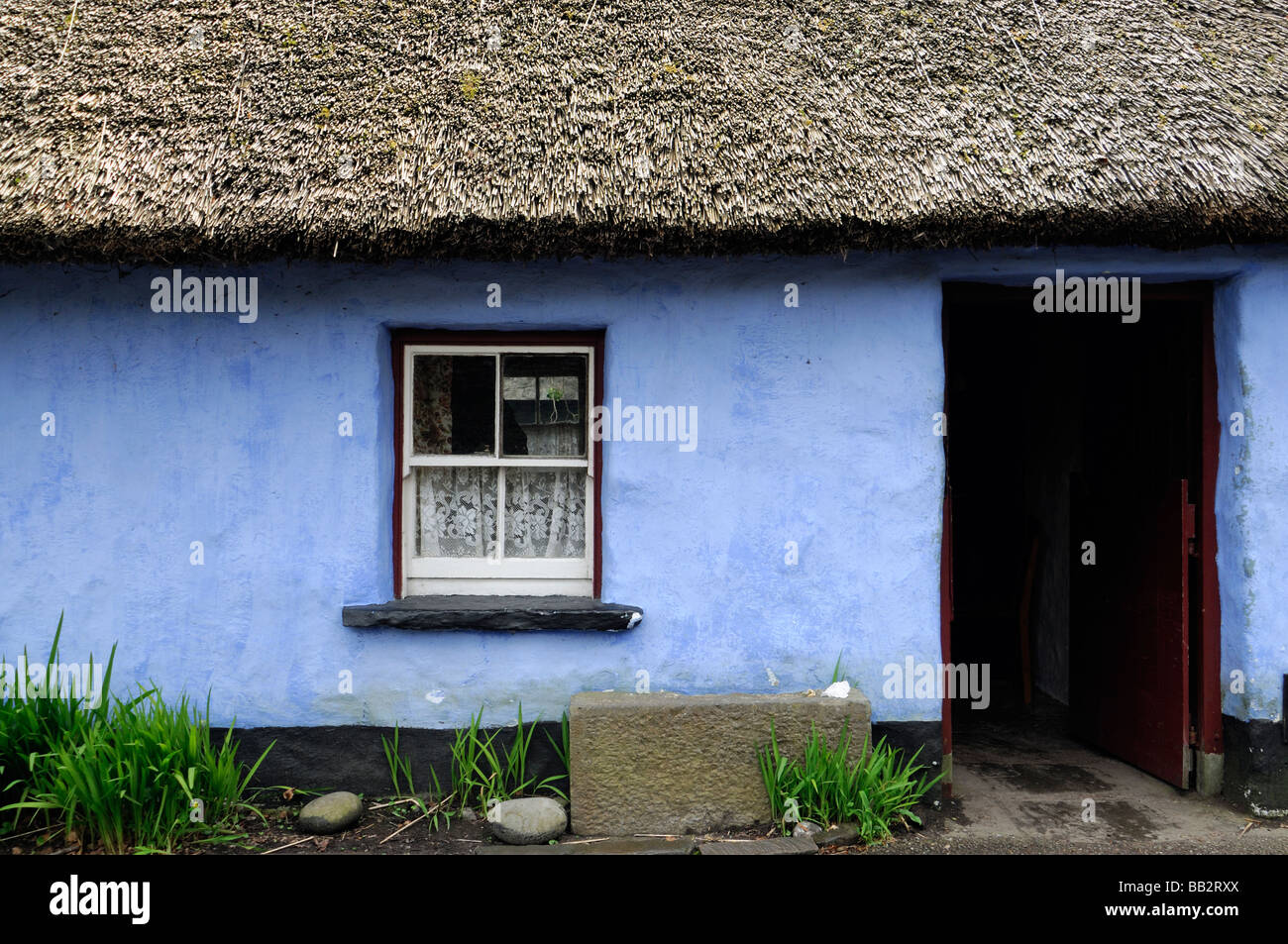 thatched roof cottage with open wooden door white window frame blue ...