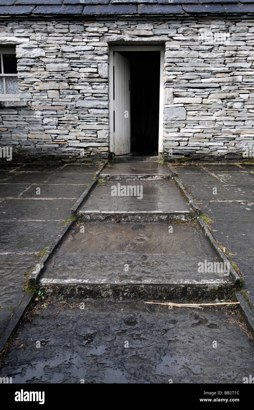slate wall cottage with open wooden door slate slab pathway leading up ...