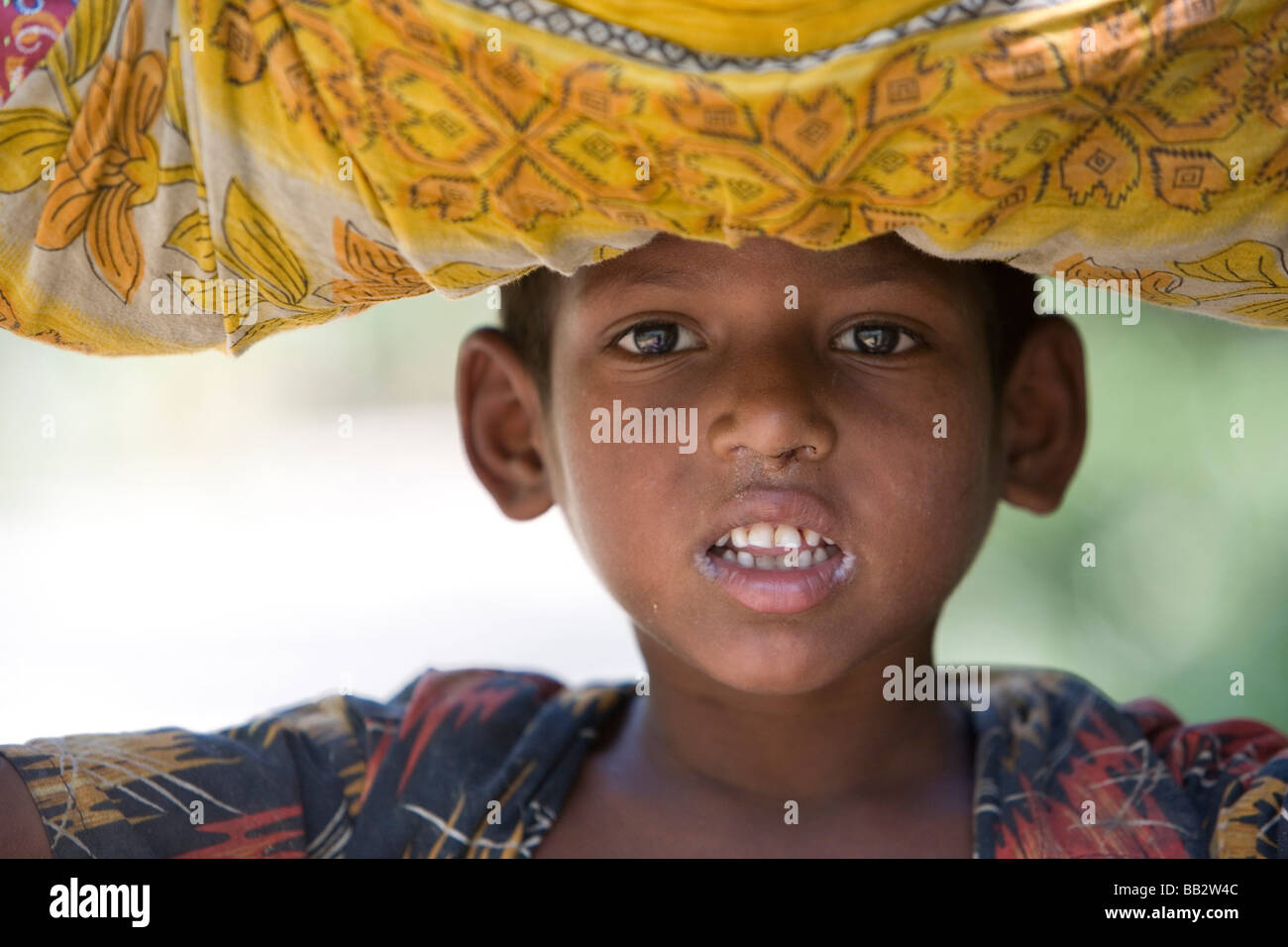 Daily Life in Bangladesh; Portrait of a young boy carrying a package on ...