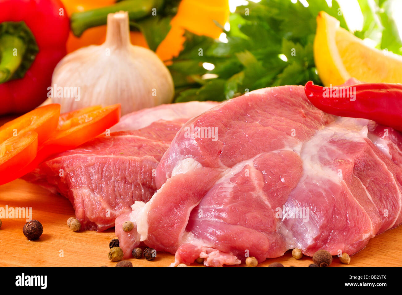 Fresh raw pork on board with vegetables, red pepper, garlic, parslay ...