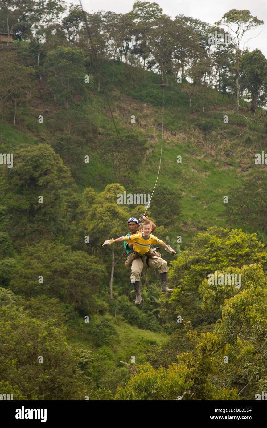 South America, Ecuador, Mindo. Boy tourist (age 9) and guide riding zip ...