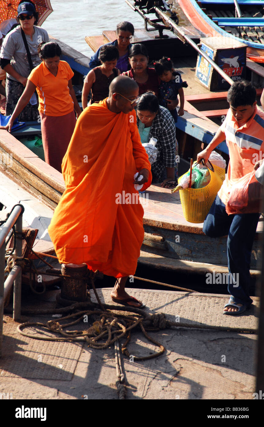 man helping monk get down from boat at pier in ranong, thai burmese ...