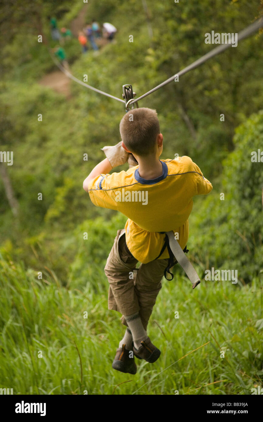 South America, Ecuador, Mindo. Boy tourist (age 9) riding zip-line ...