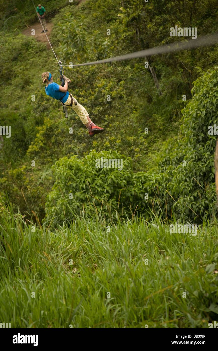 South America, Ecuador, Mindo. Girl tourist (age 7) riding zip-line ...