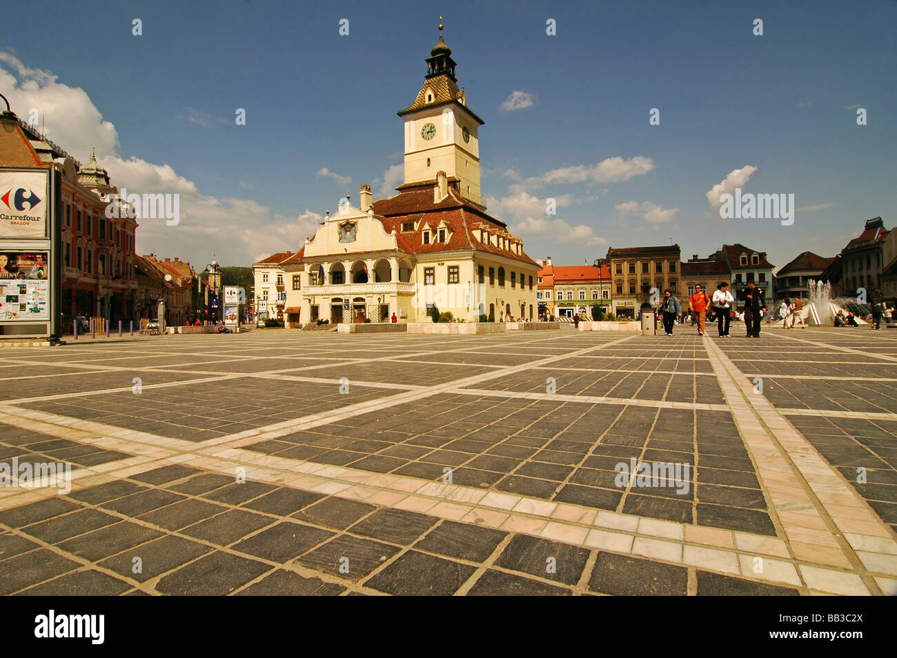 ROMANIA, Brasov. Main town square with tled cement ground, a church in ...