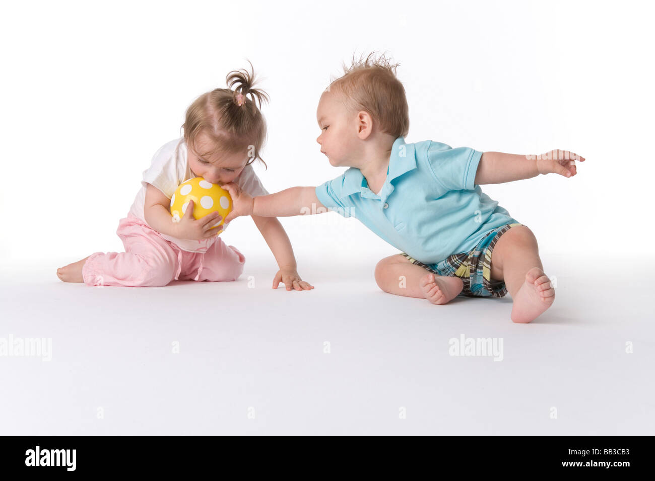 Two toddlers playing with a ball Stock Photo - Alamy