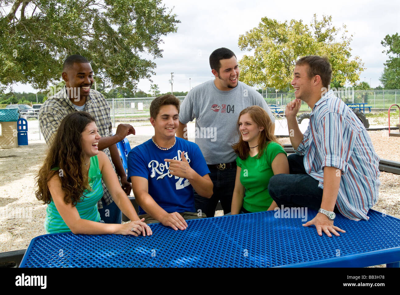 Group of teenage students talking outside on picnic table Stock Photo ...